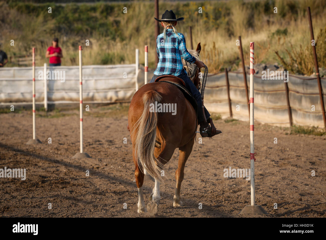 Young woman riding a horse through a rodeo arena during a youth rodeo ...