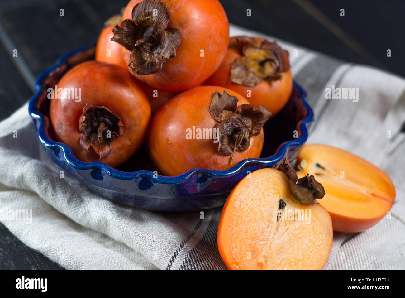 Ripe orange hachiya persimmons in blue bowl Stock Photo - Alamy