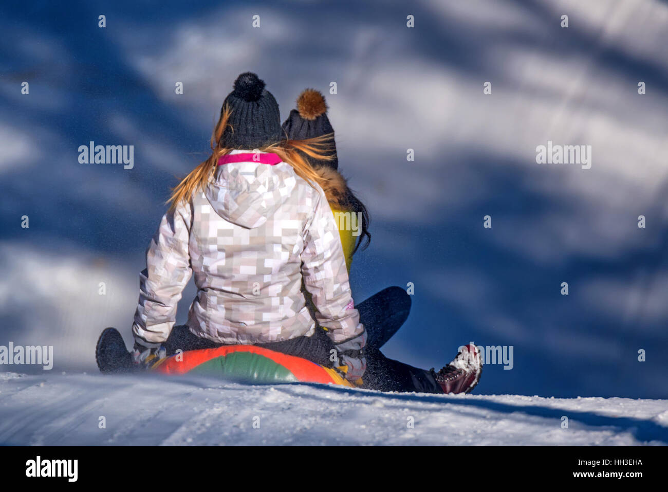 Girls sledding down a snowy hill Stock Photo - Alamy