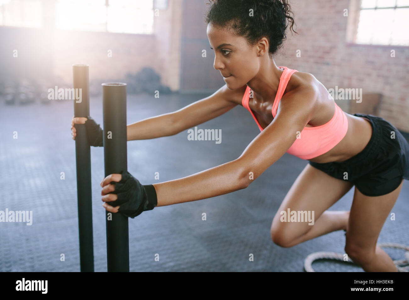Side view shot of fit young woman pushing the sled at gym. African ...