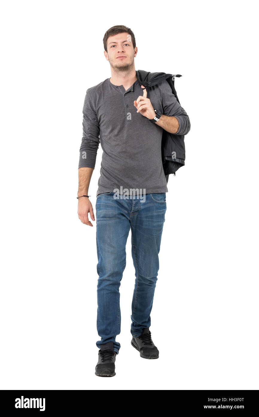 Casual young man walking forward carrying jacket over shoulder looking ...