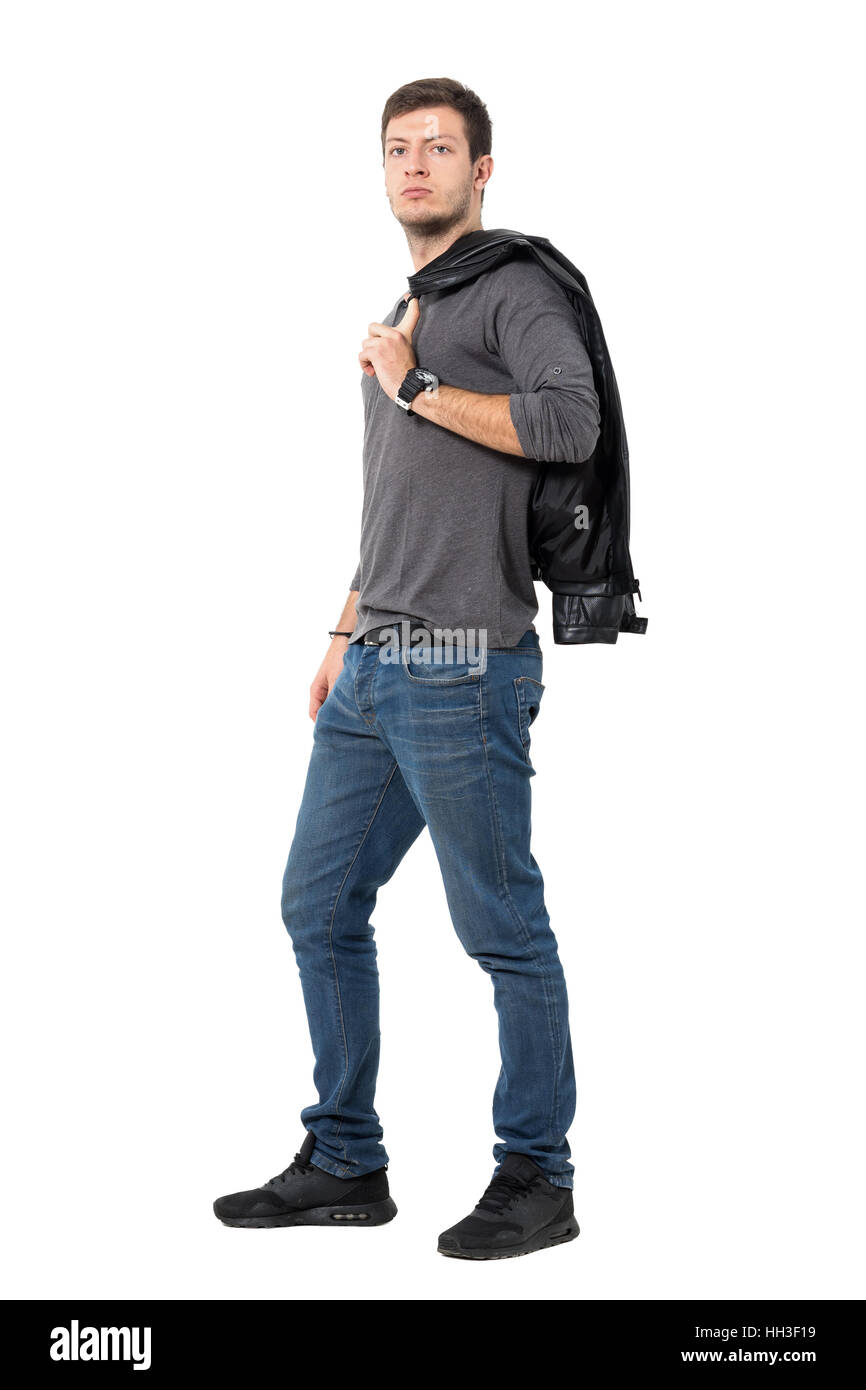 Side view of casual young man carrying jacket over shoulder looking at ...