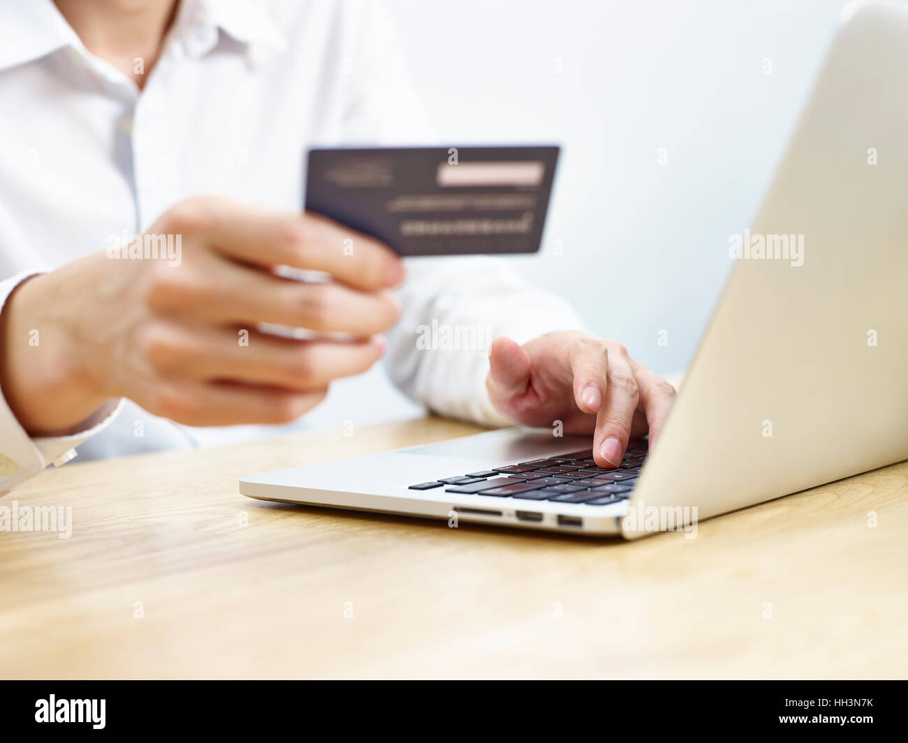 young man entering credit card information while shopping online using ...
