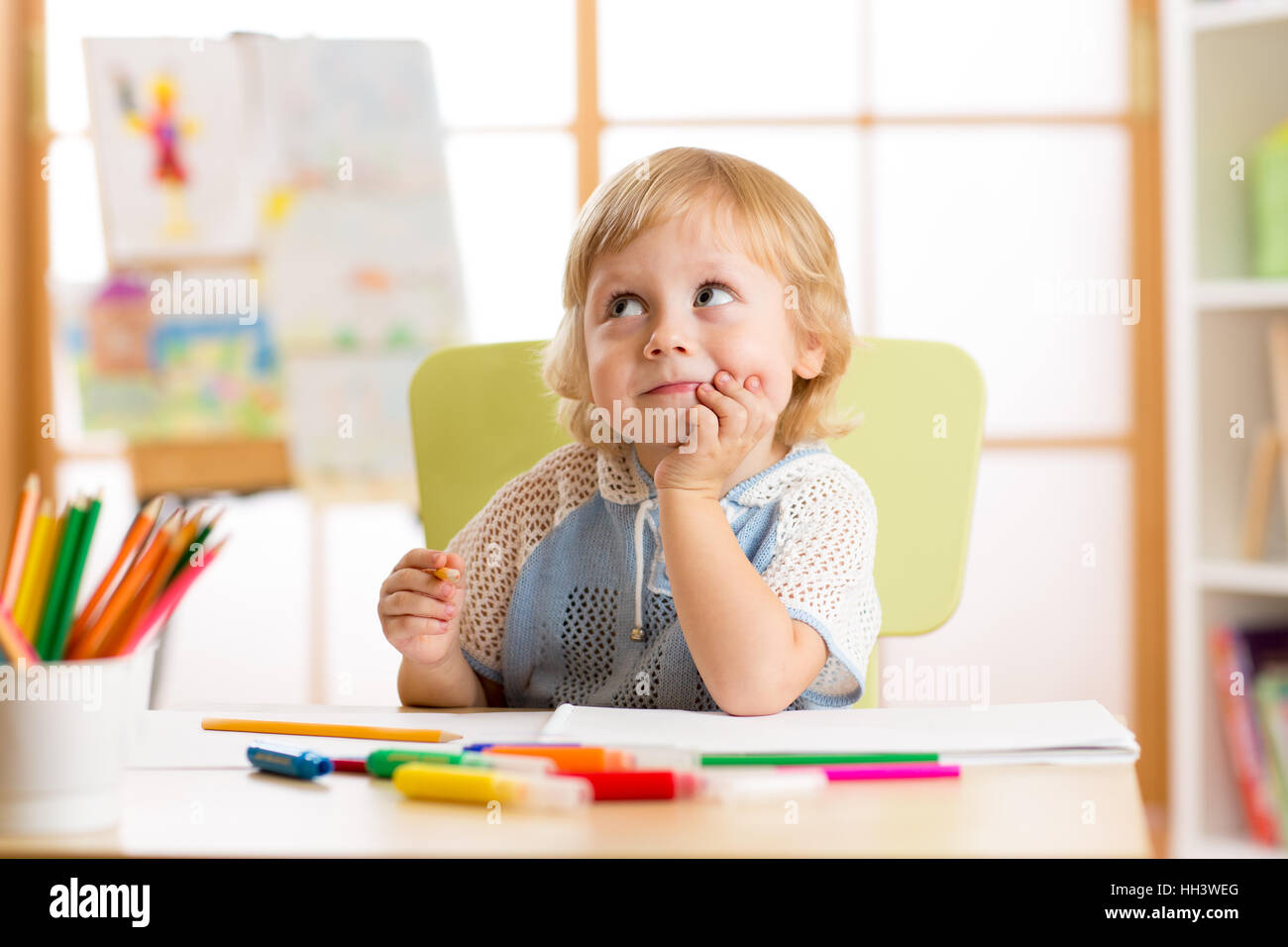 Smiling child having an idea while drawing Stock Photo - Alamy