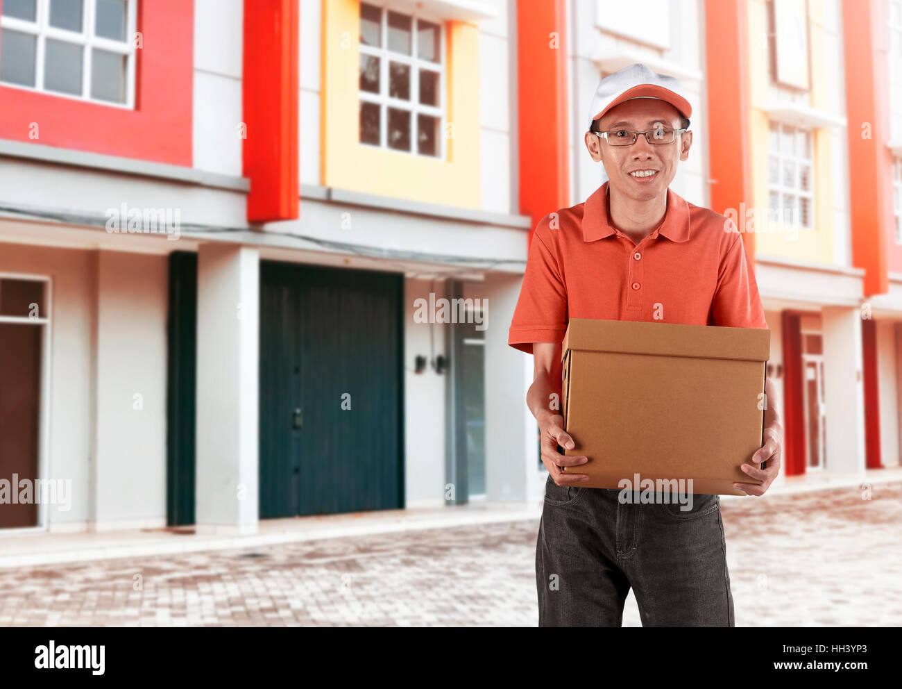 Smiling asian delivery man holding package to delivered Stock Photo - Alamy