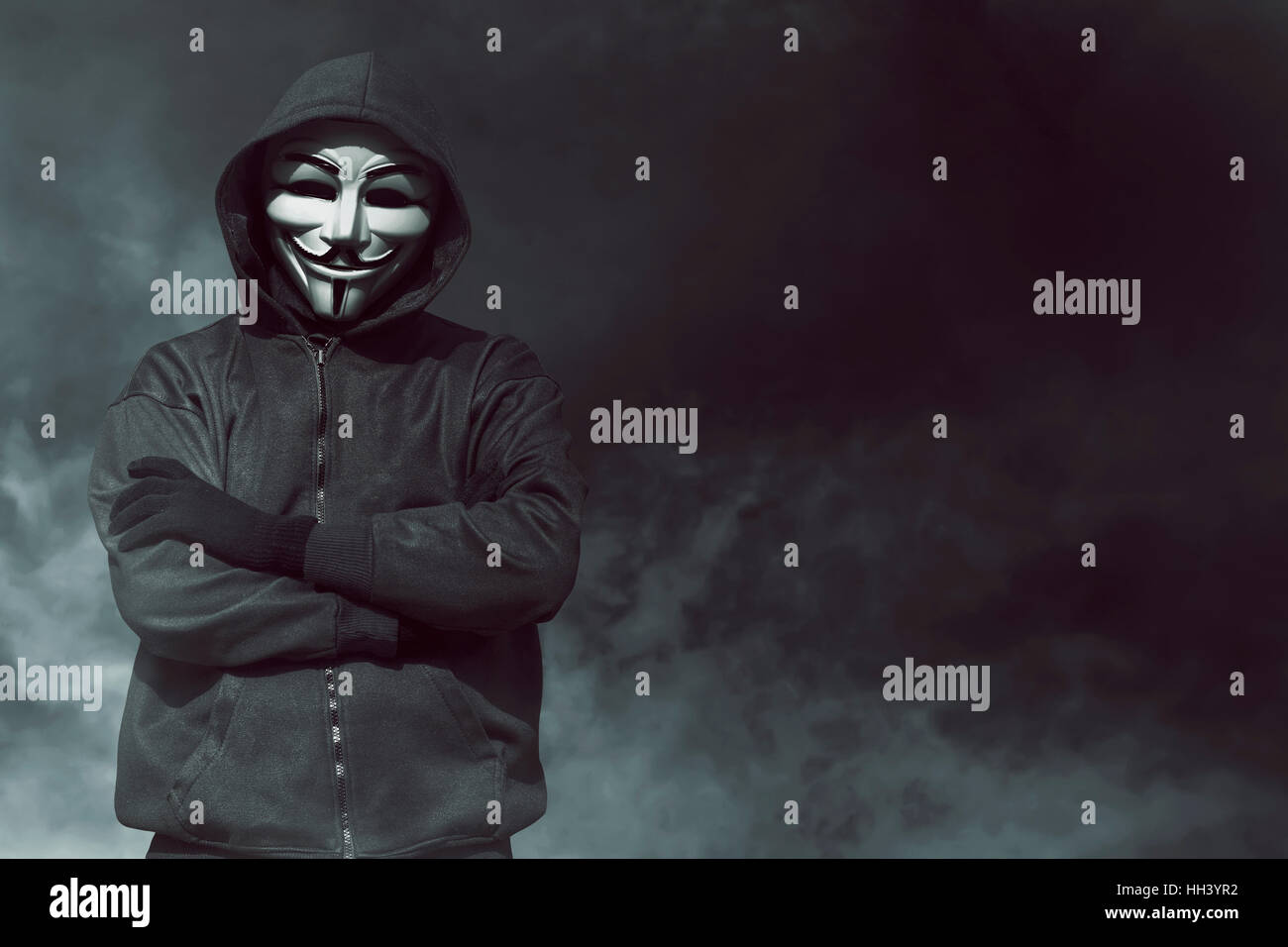 Hooded man with mask standing alone in the empty dark room Stock Photo ...
