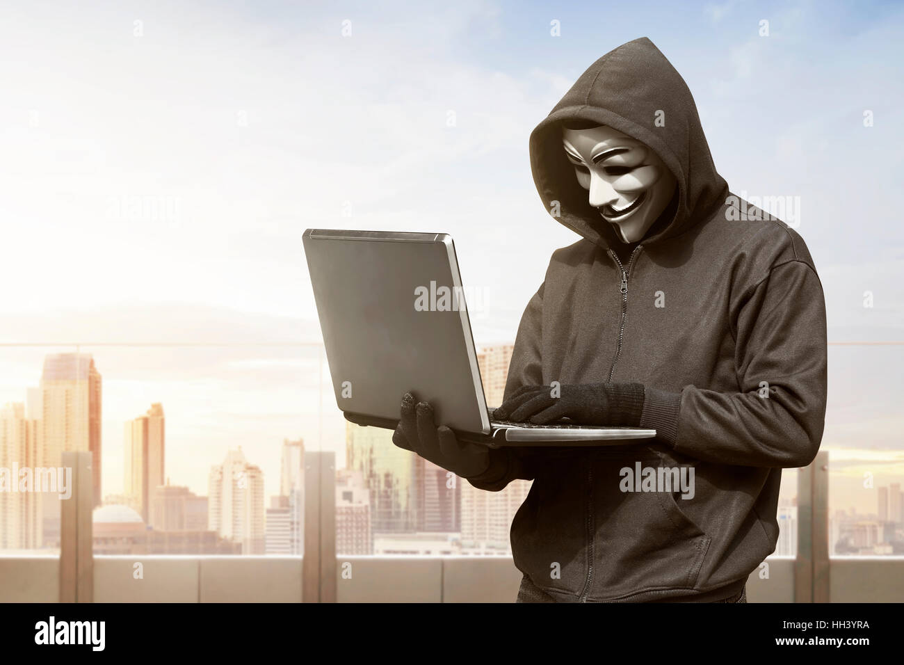 Hacker man with anonymous mask using laptop to hacking in the modern ...