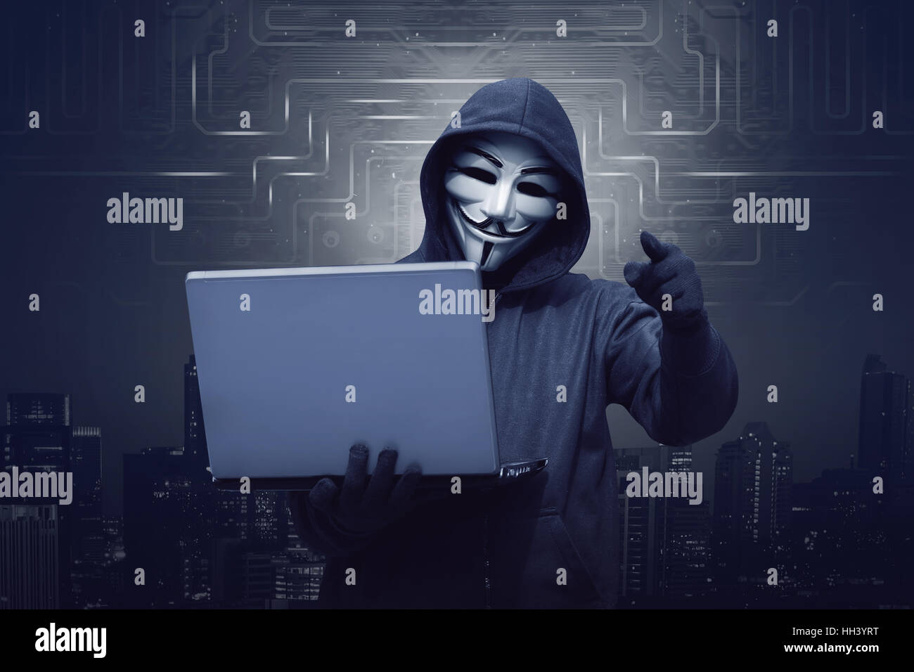 Hacker man with mask holding laptop while appoint against virtual ...
