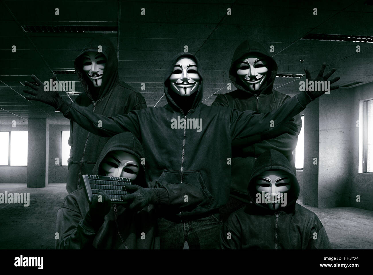 Group of hooded hacker with mask standing in the dark room background ...