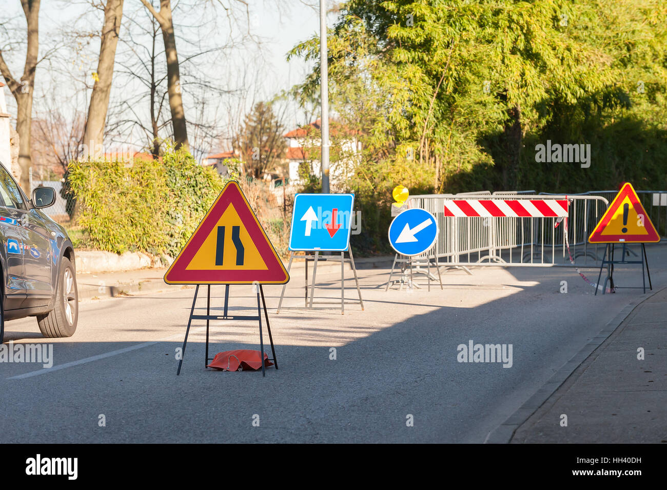 Road sign lane narrowing. In the background, blurred a roadworks site ...