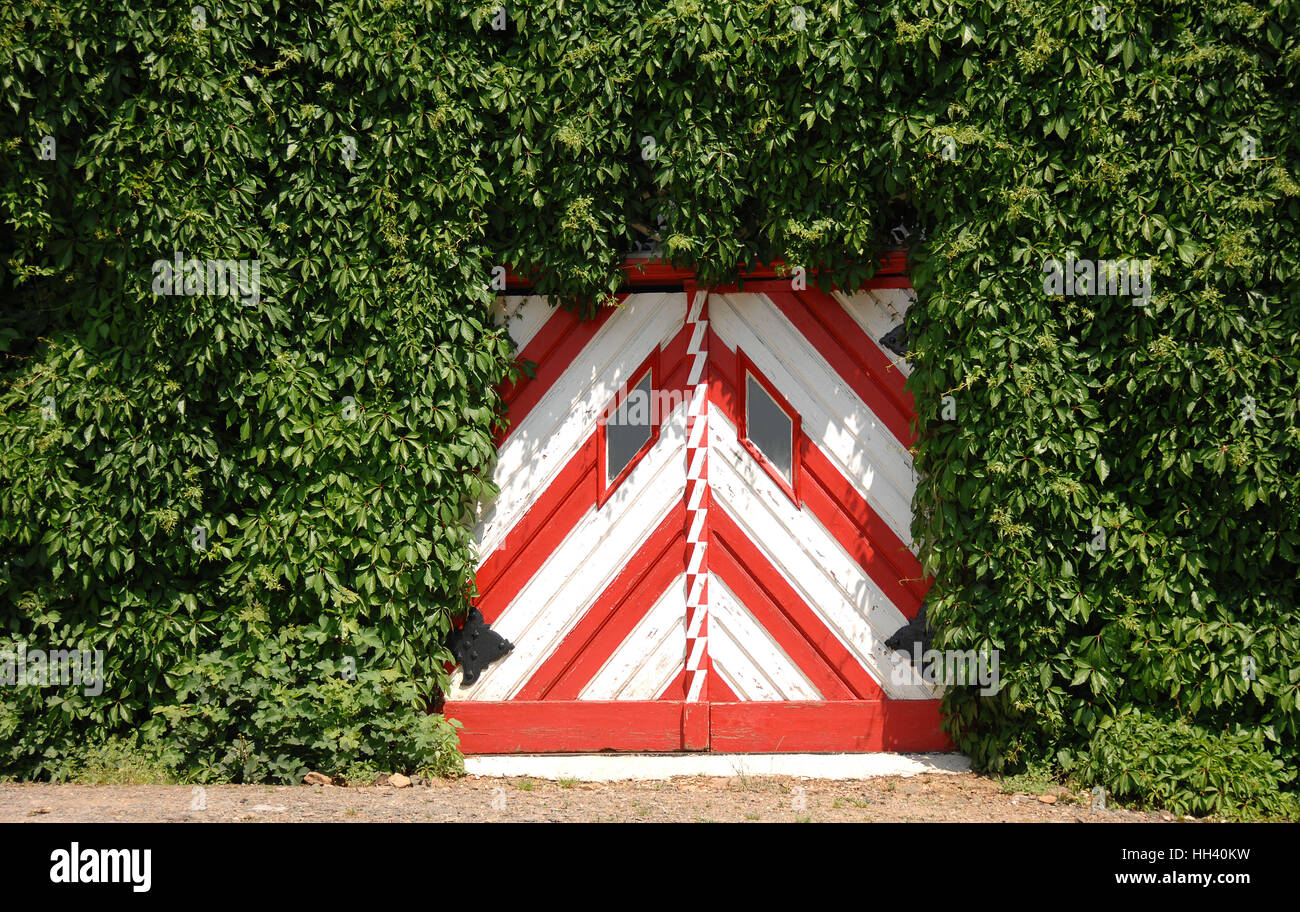 Two-winged wooden gate with red white stripes in a placid wall Stock ...