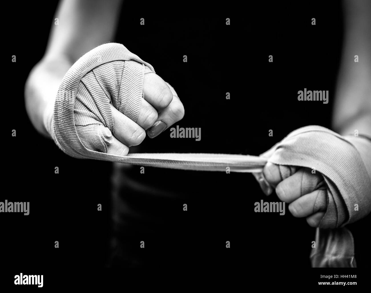 Woman is wrapping hands with pink boxing wraps. Isolated on black with ...
