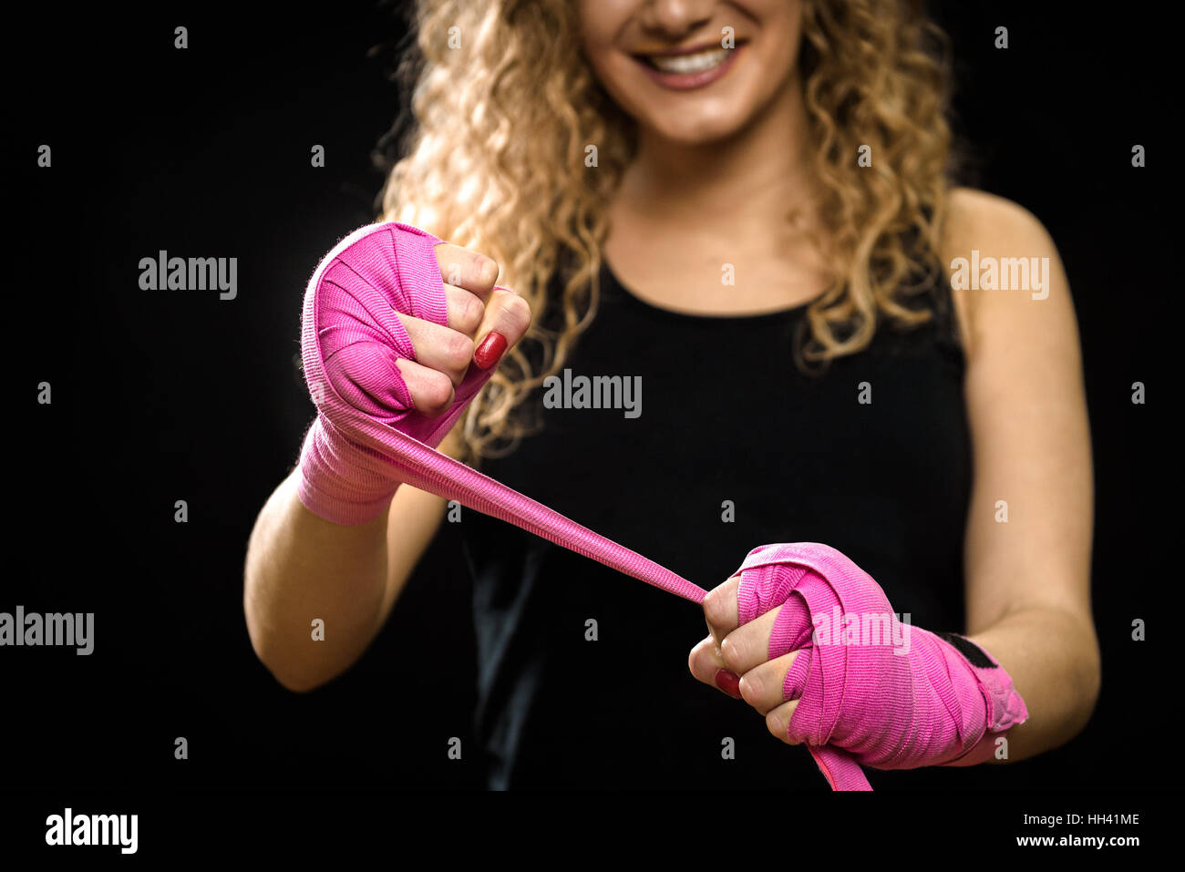 Atractive Woman is smiling and wrapping hands with pink boxing wraps ...