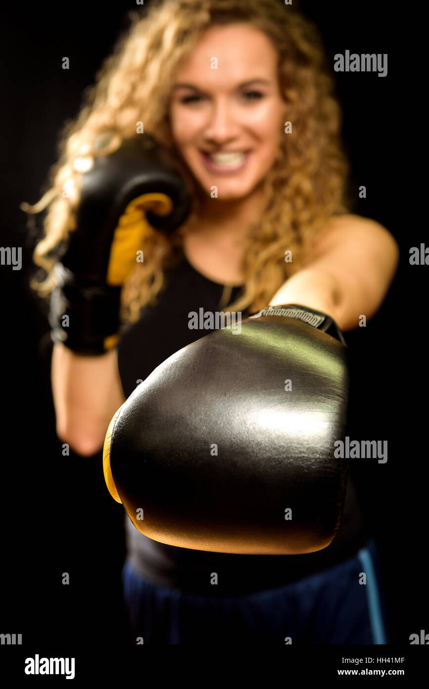 Attractive blond woman is punching with boxing glove. Curly hair and ...