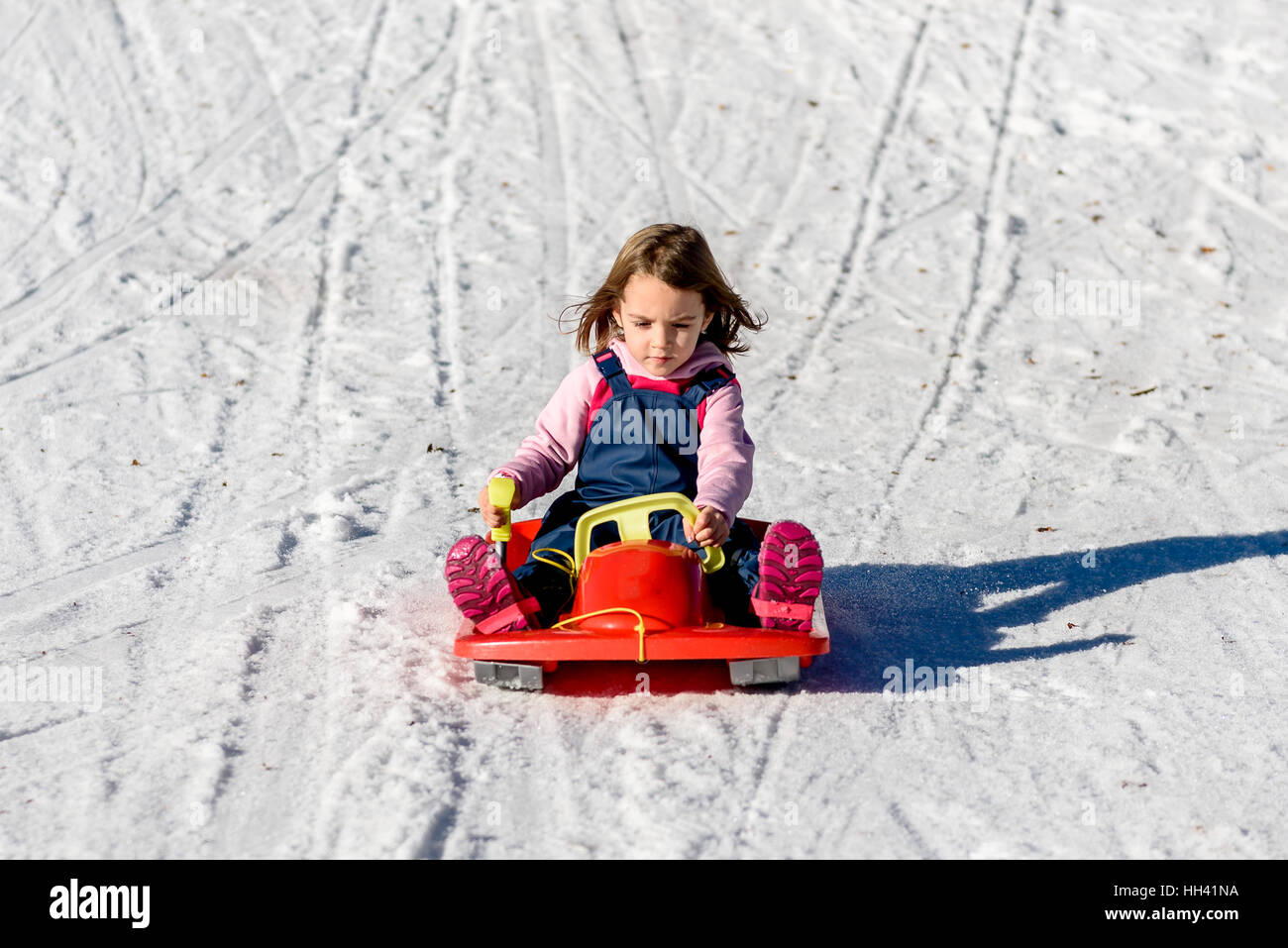 Little girl sliding with bob in the snow in wintertime. Winter vacation ...