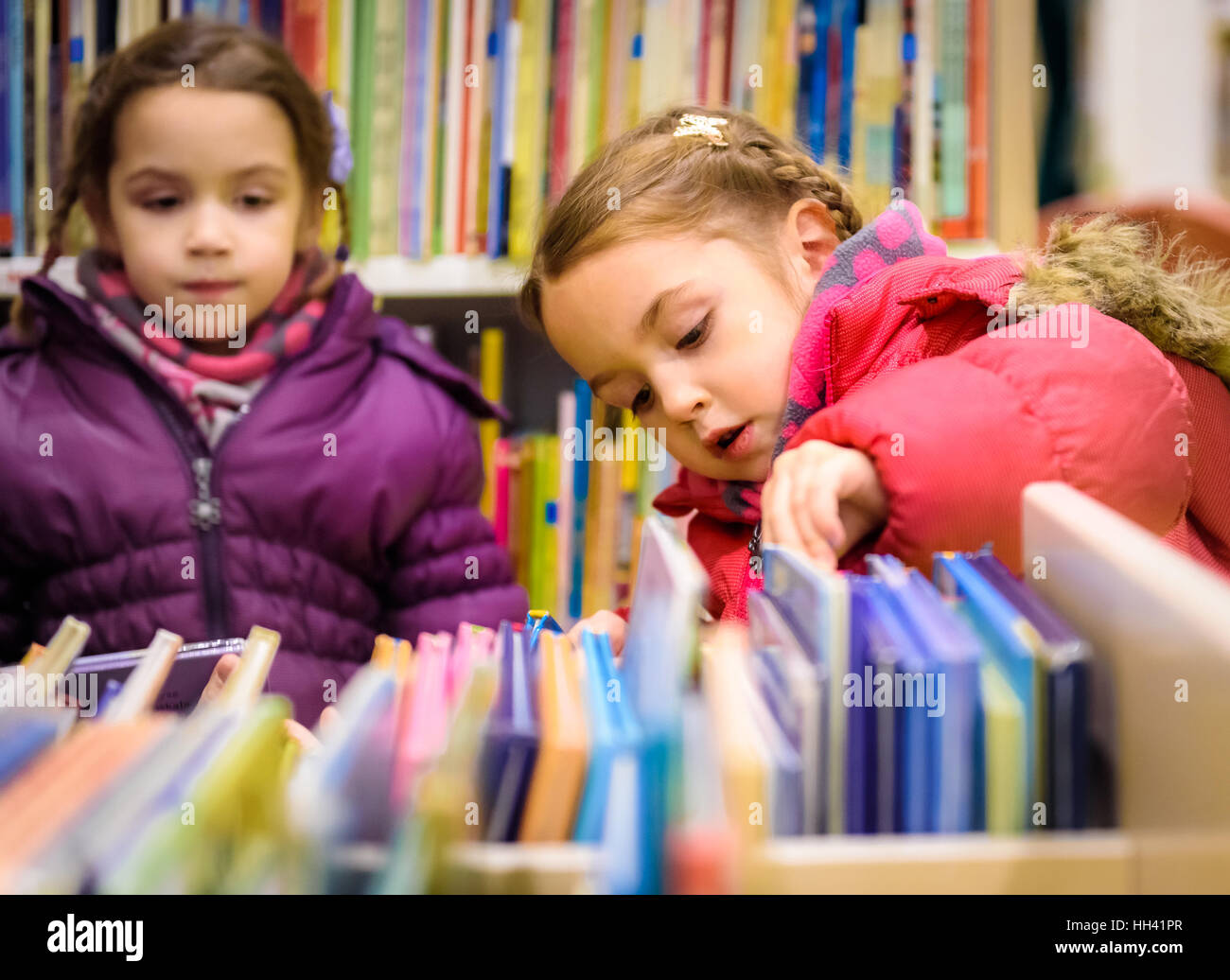 Little girl is choosing a book in the library. A child is looking at ...