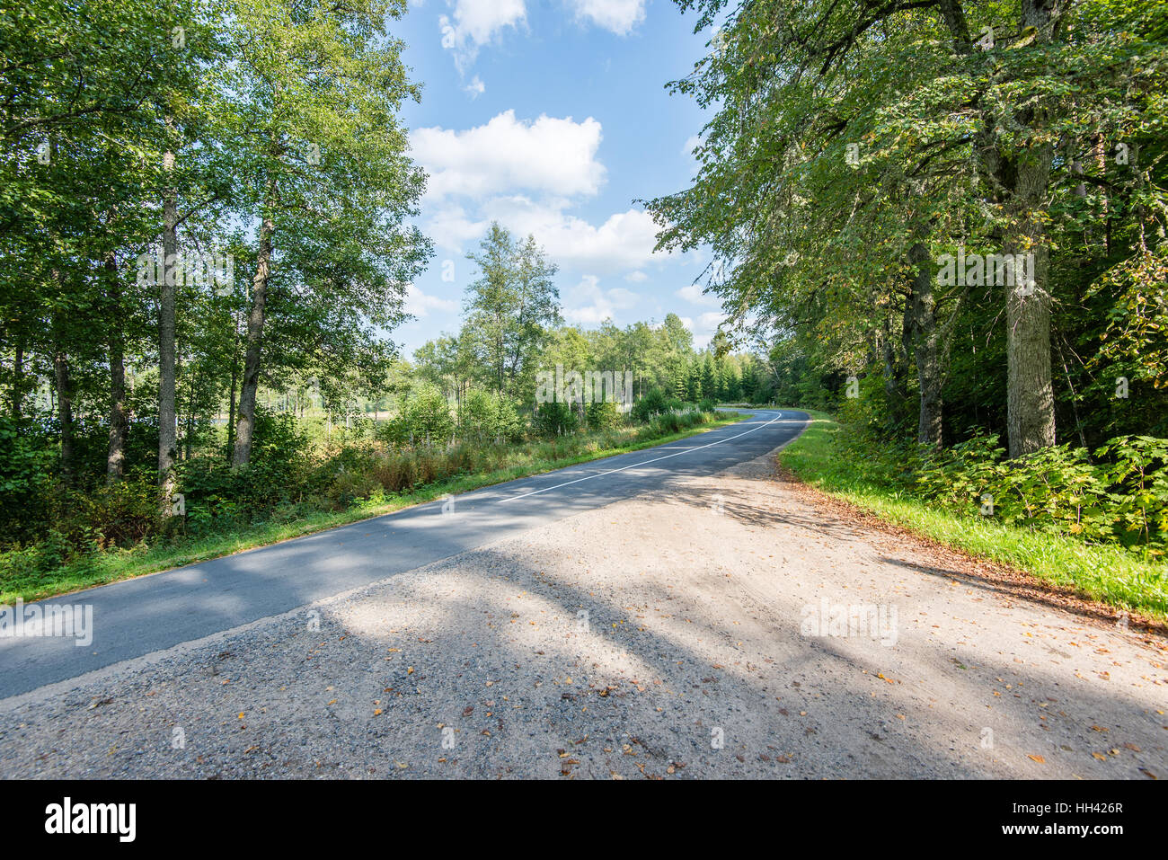 Winding country Road with clouds above and dry tarmac Stock Photo - Alamy