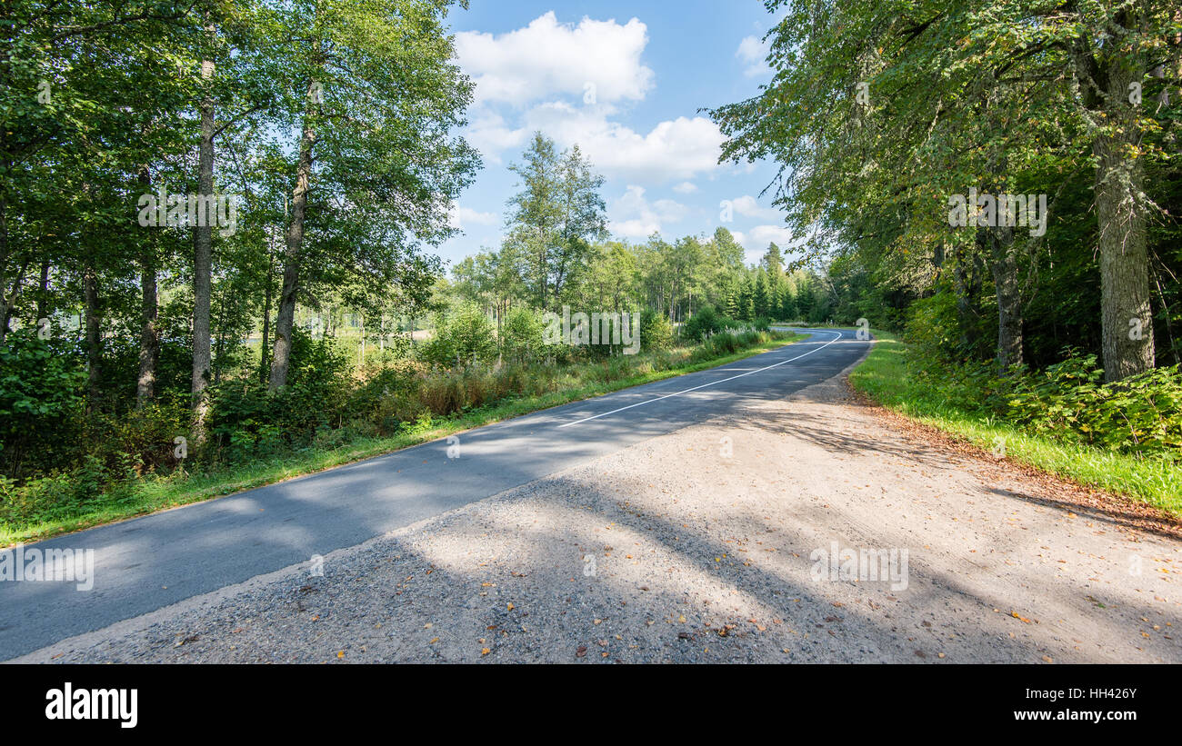 Winding country Road with clouds above and dry tarmac Stock Photo - Alamy
