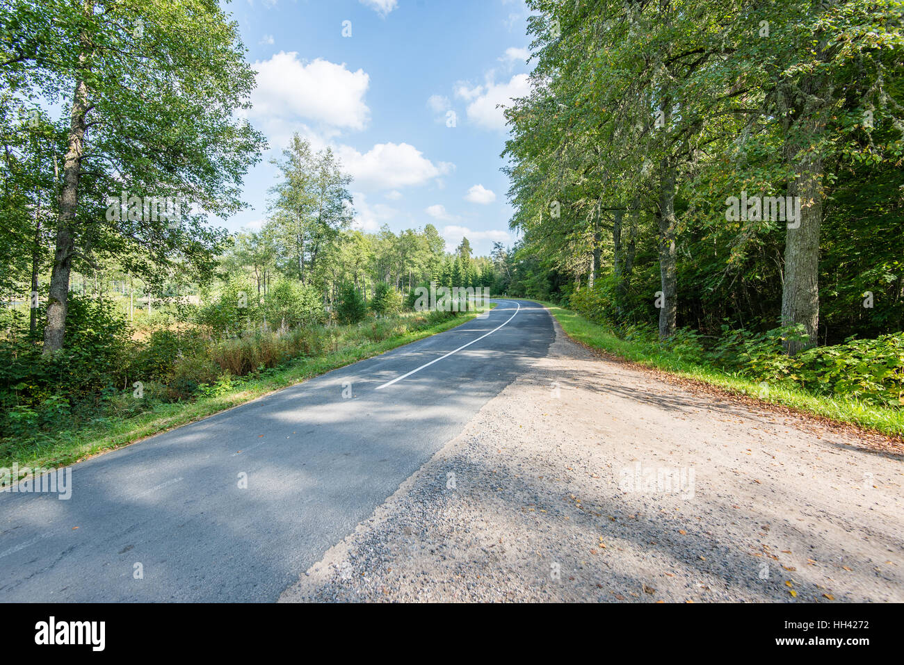 Winding country Road with clouds above and dry tarmac Stock Photo - Alamy