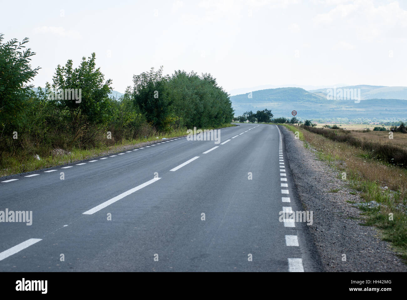 Winding country Road with clouds above and dry tarmac Stock Photo - Alamy