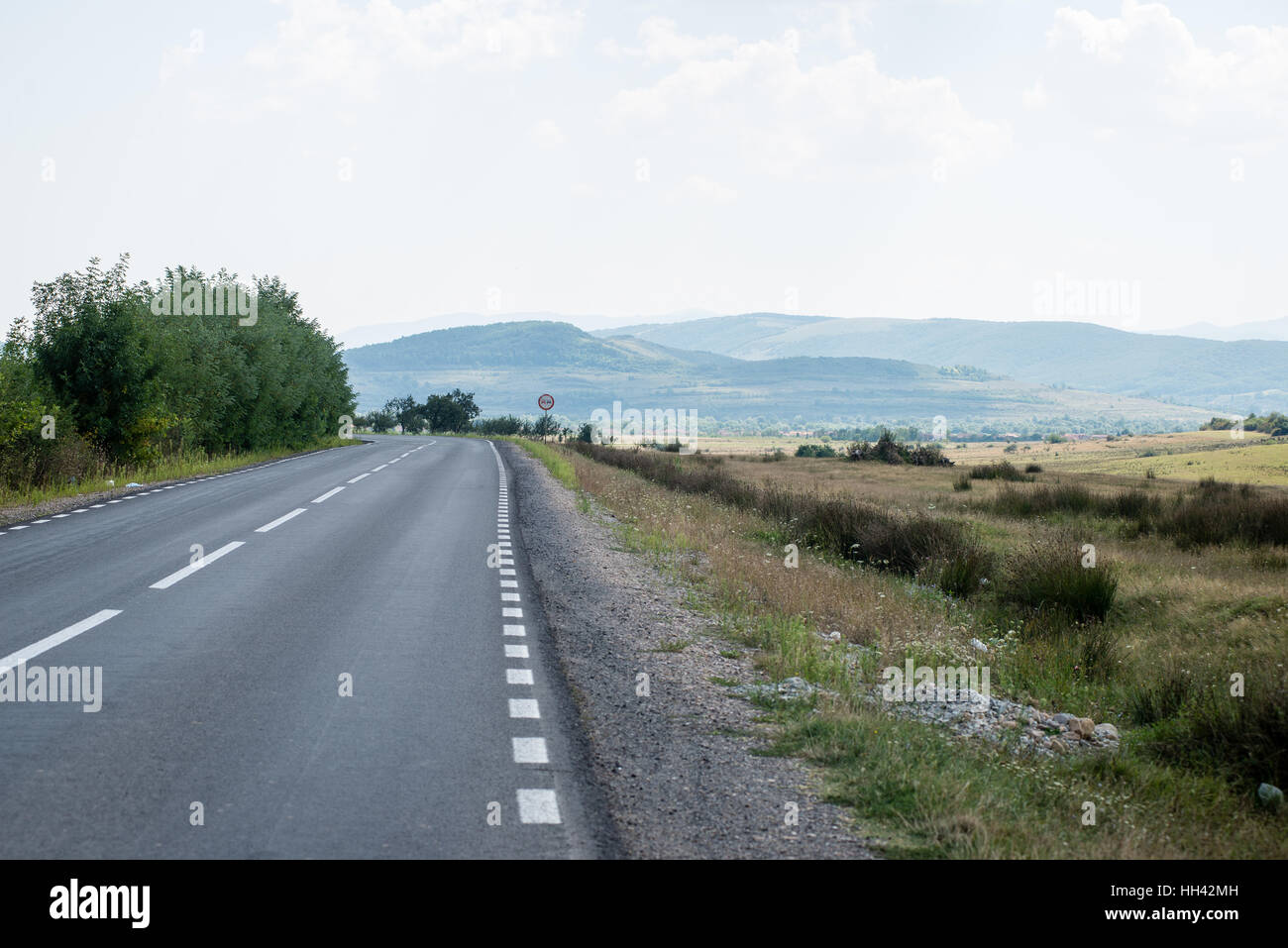 Winding country Road with clouds above and dry tarmac Stock Photo - Alamy