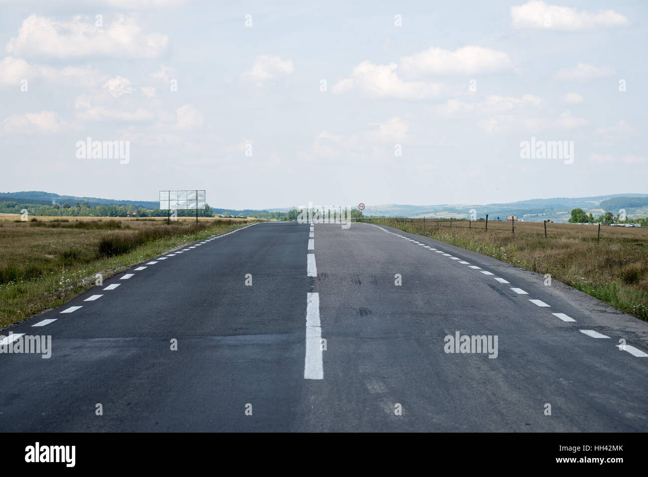 Winding country Road with clouds above and dry tarmac Stock Photo - Alamy