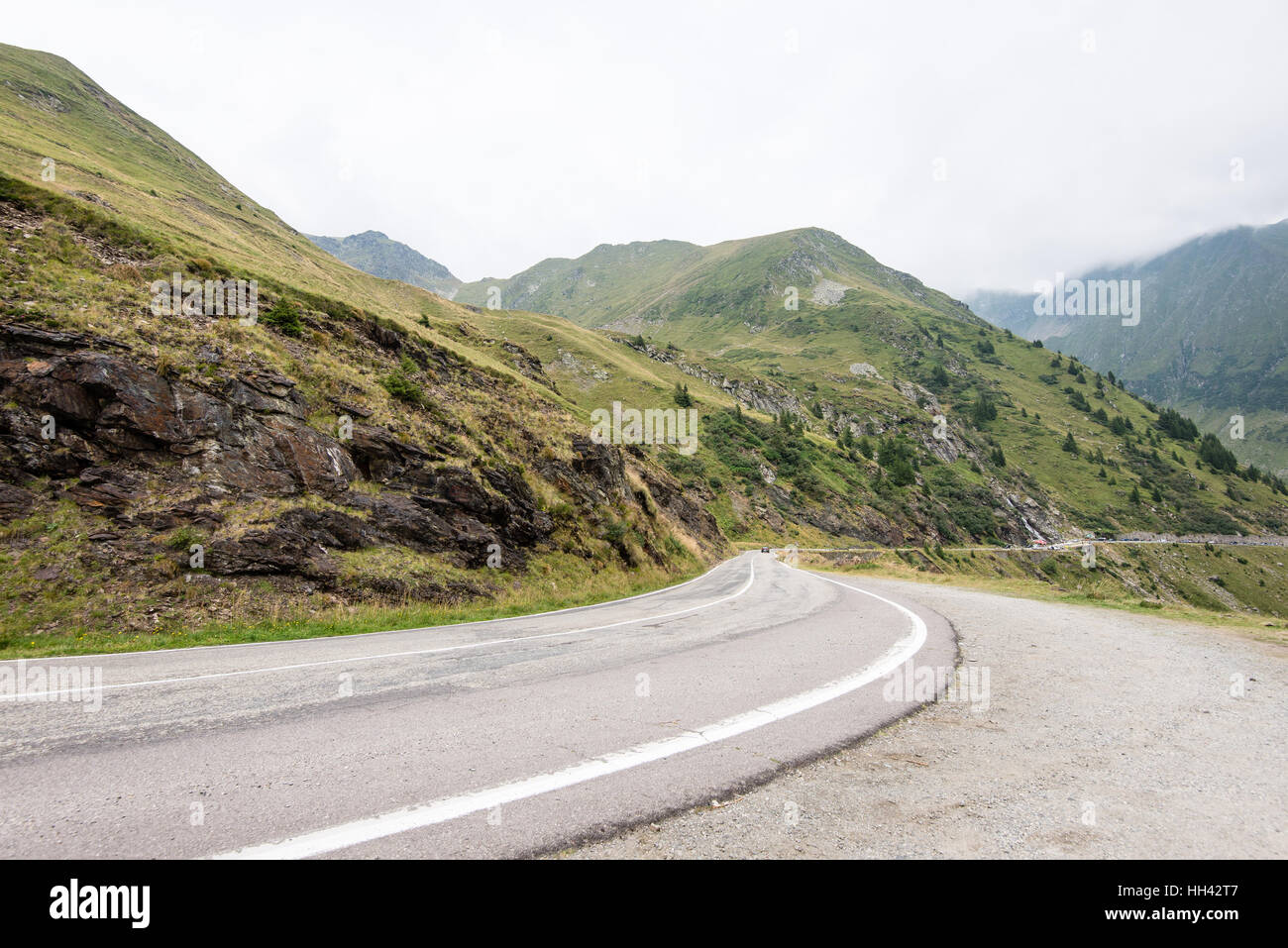 Winding country Road with clouds above and dry tarmac Stock Photo - Alamy