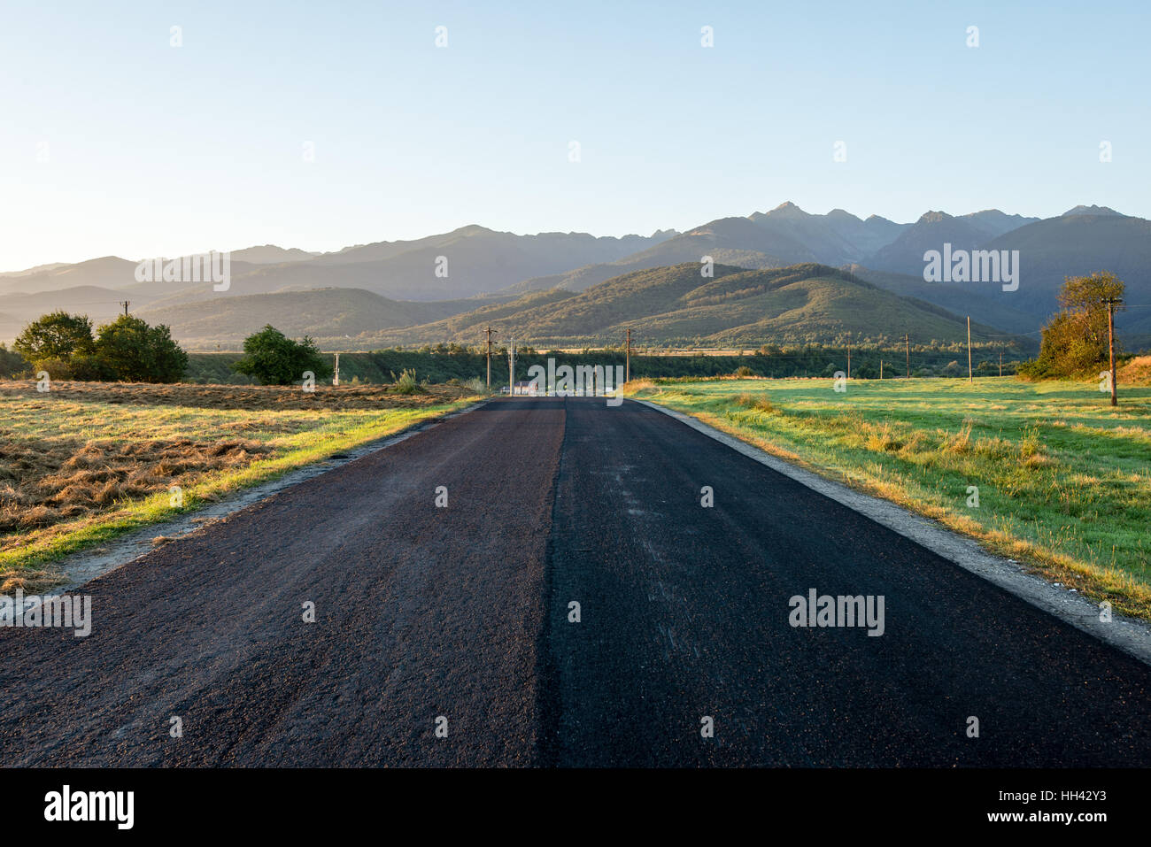 Winding country Road with clouds above and dry tarmac Stock Photo - Alamy