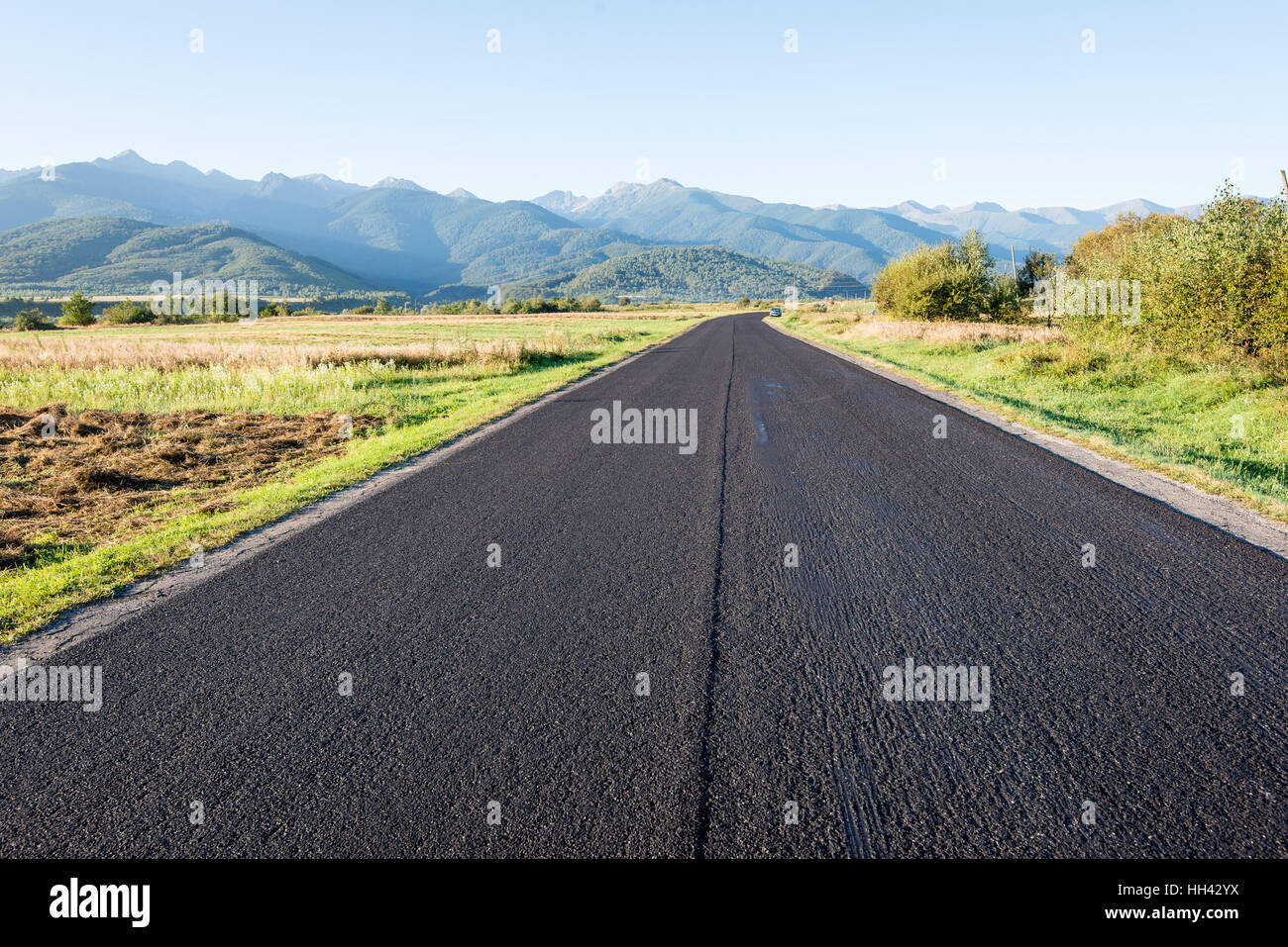 Winding country Road with clouds above and dry tarmac Stock Photo - Alamy
