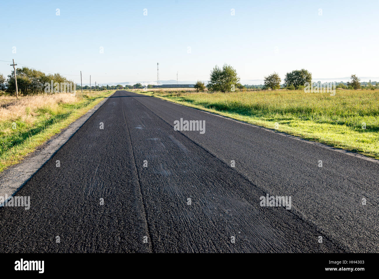 Winding country Road with clouds above and dry tarmac Stock Photo - Alamy