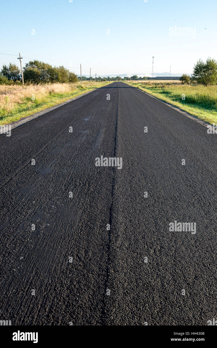 Winding country Road with clouds above and dry tarmac Stock Photo - Alamy