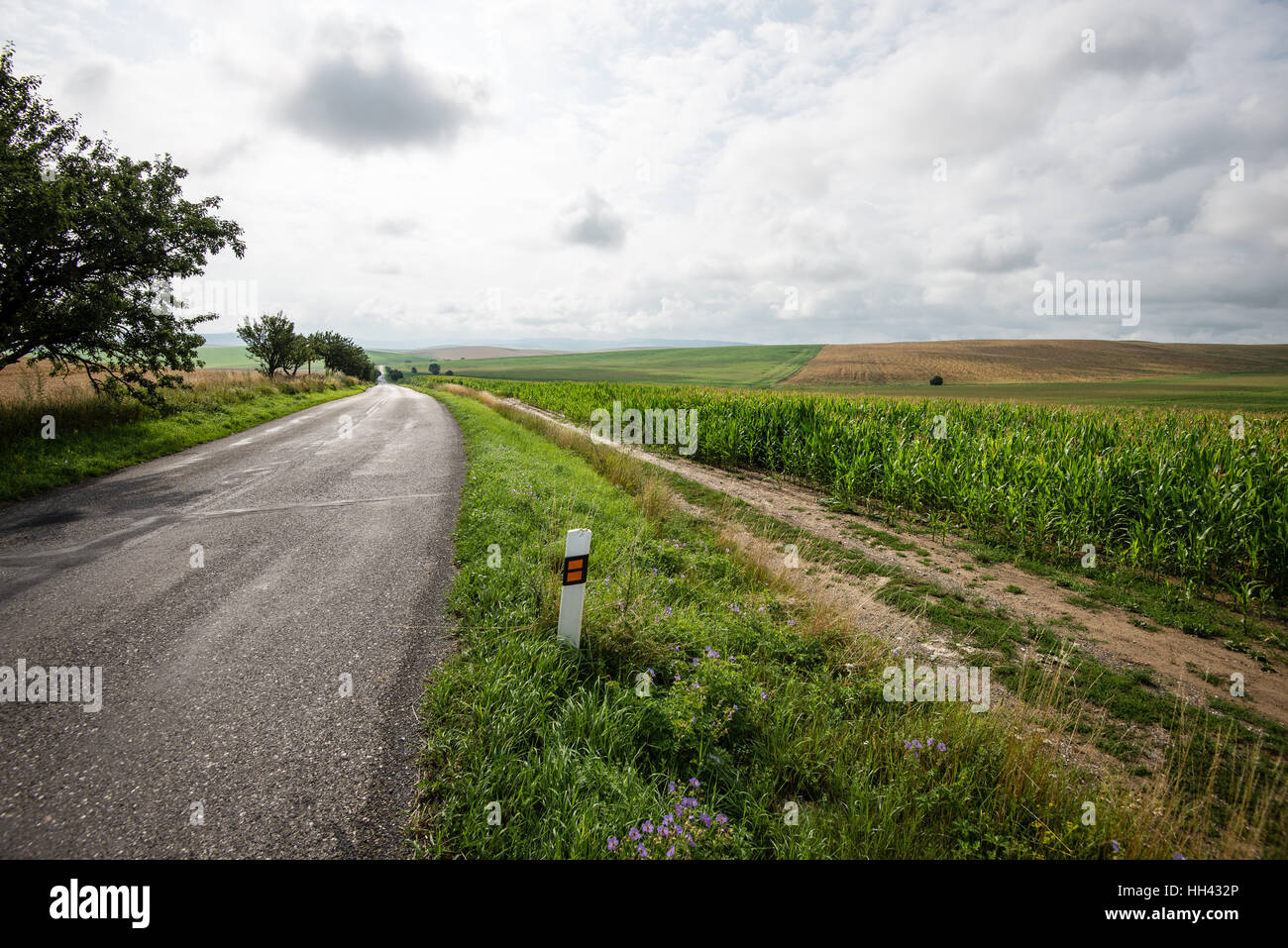 Winding country Road with clouds above and dry tarmac Stock Photo - Alamy