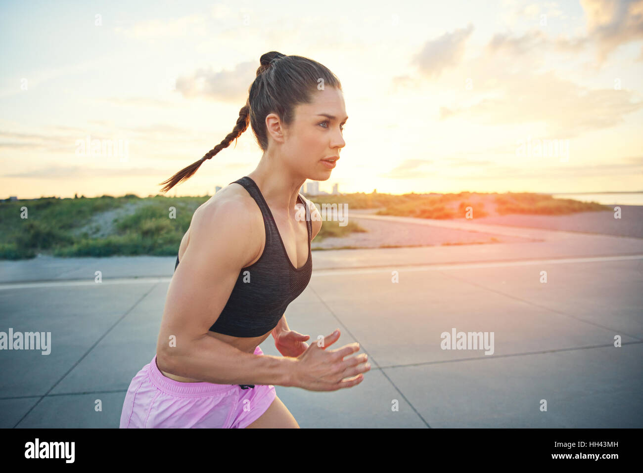 Young woman runner working out at sunrise running along a rural road at ...