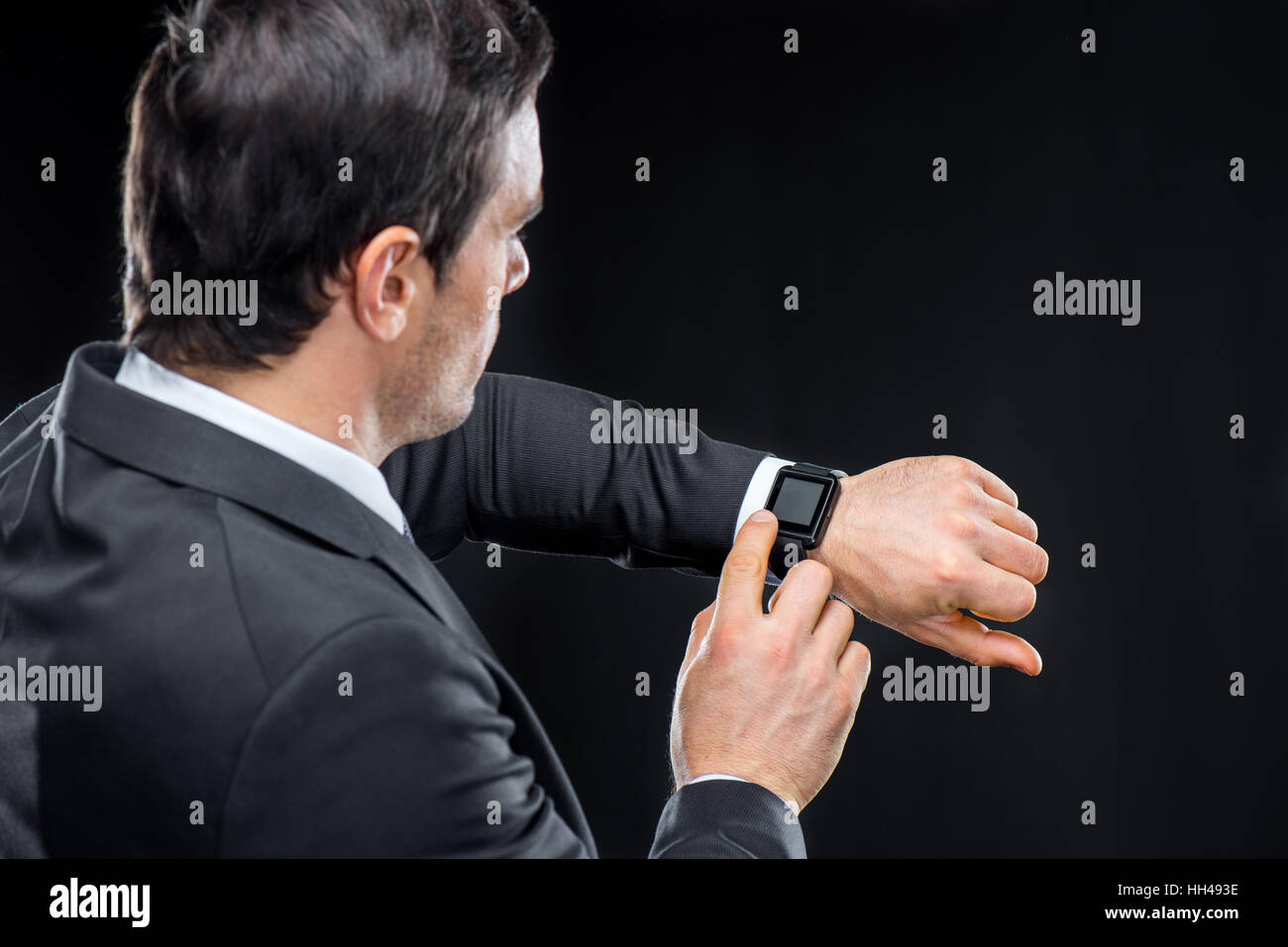 Young man looking at his smartwatch on black Stock Photo - Alamy