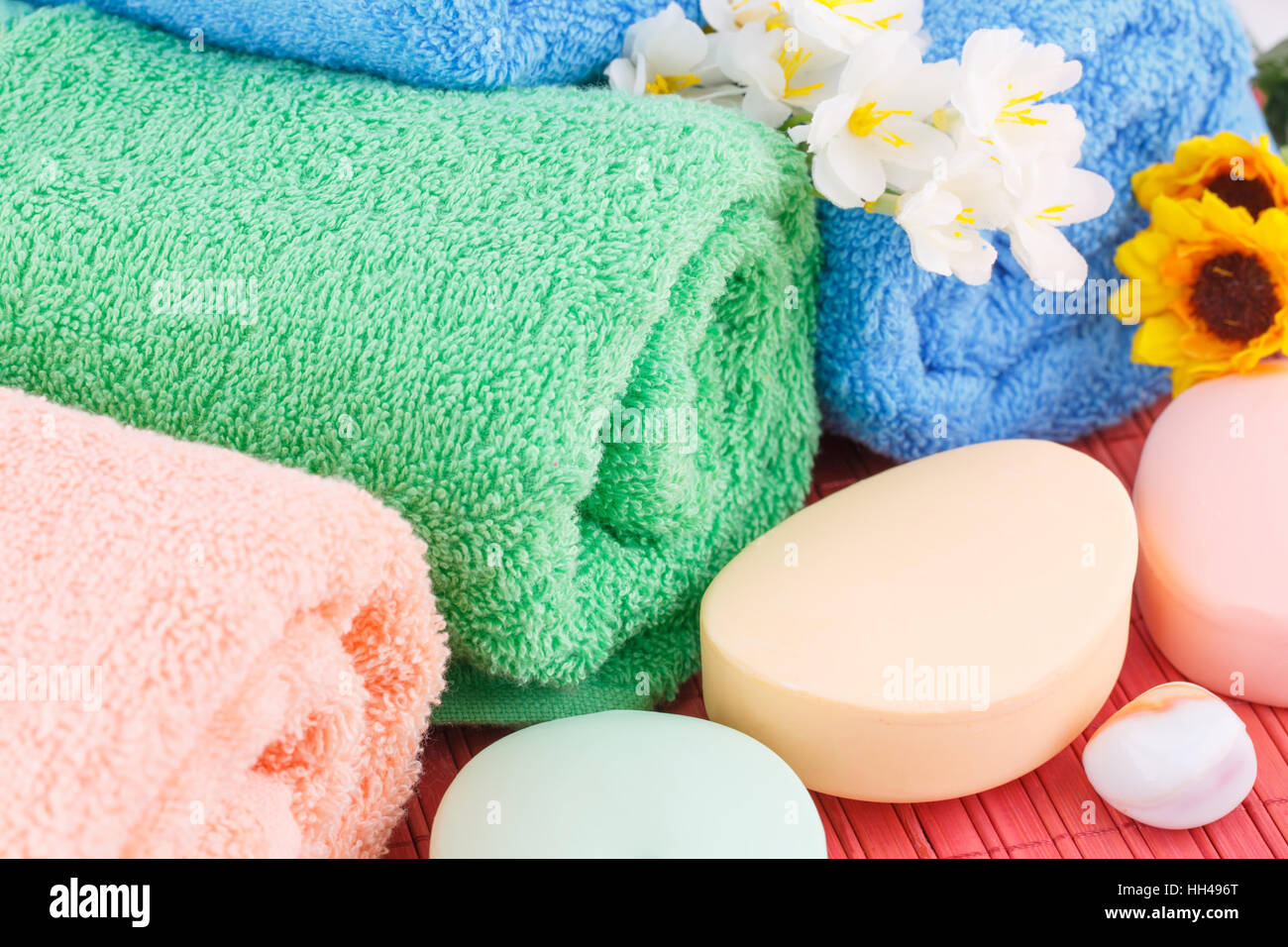 Colorful rolled towels with flowers, soaps and stones closeup picture ...
