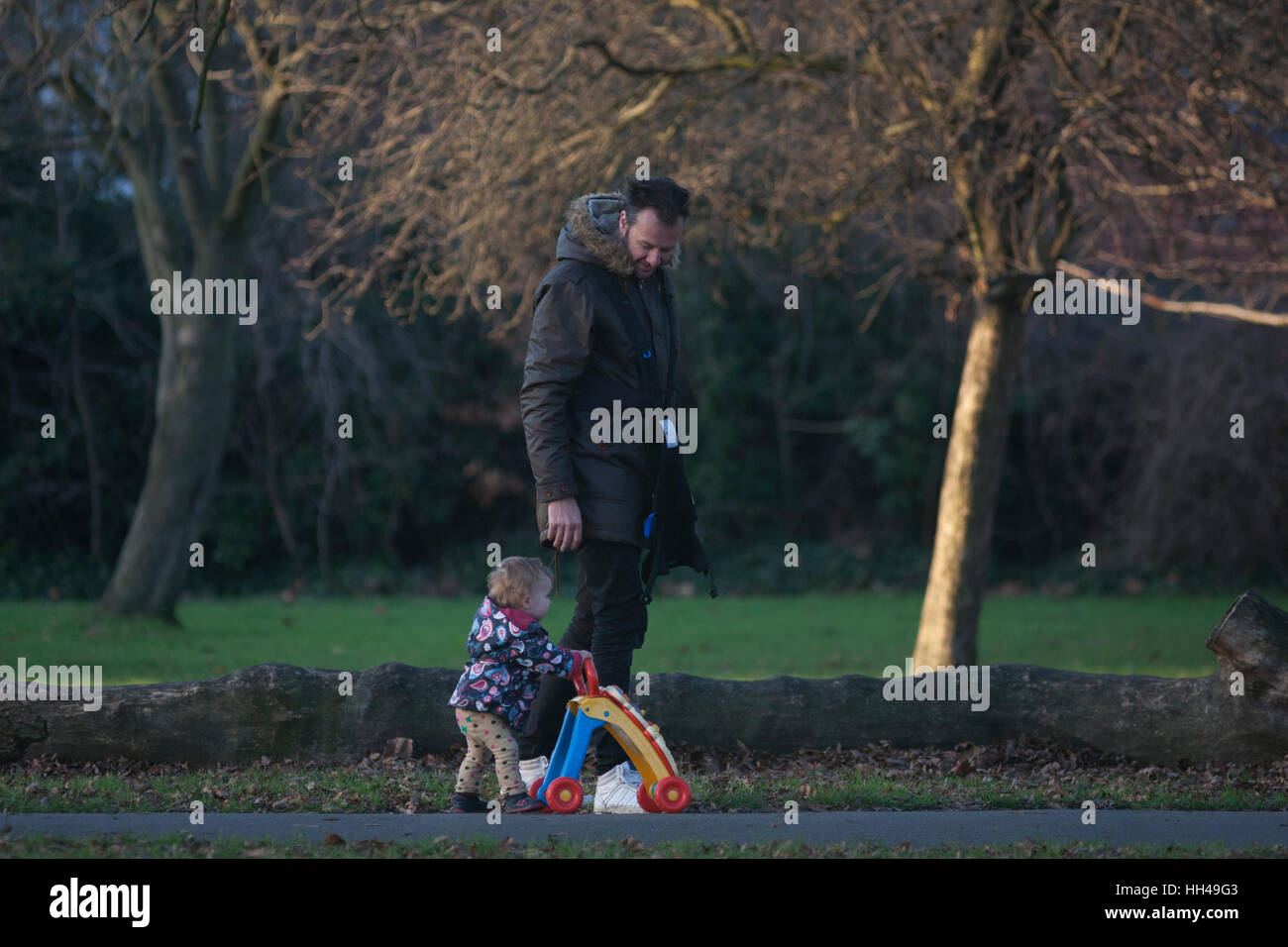 A man walks a child who follows pushing a walking trolley, on 5th ...