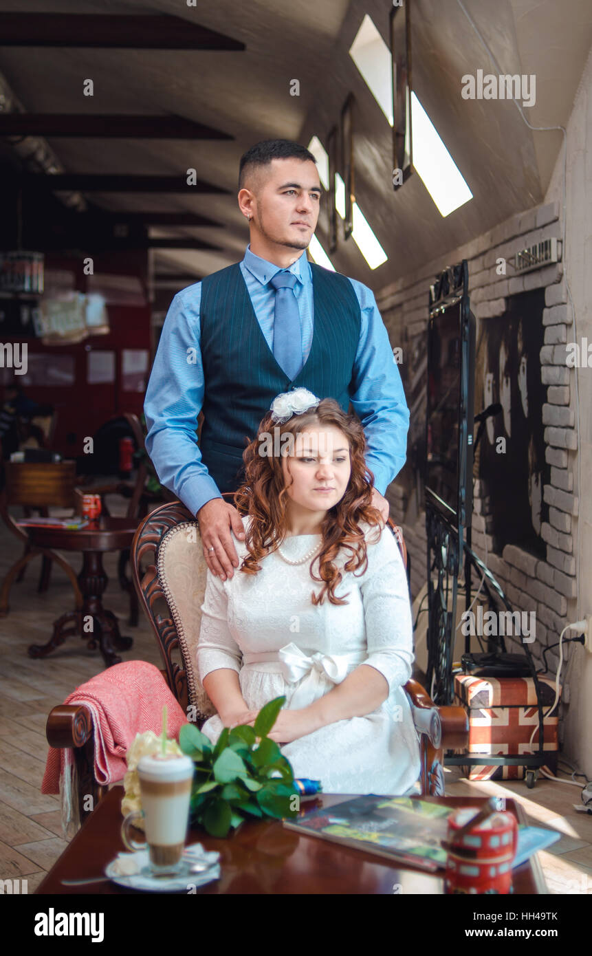 The young man embraces the girl who sits in a chair at a window Stock ...