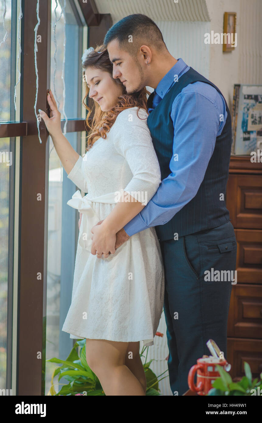 The young loving couple embraces and are by the big window. Wedding ...