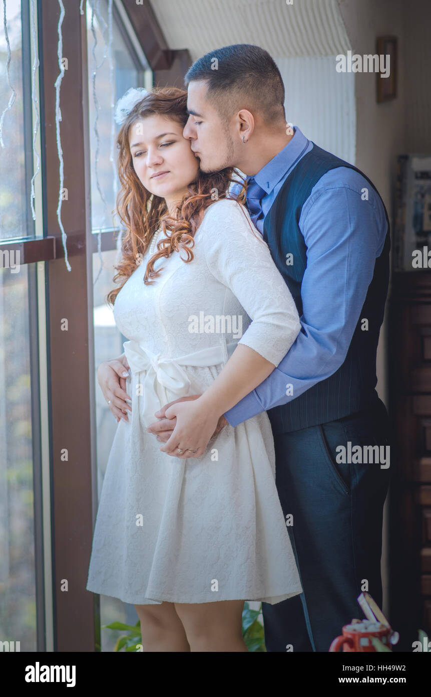 The young loving couple embraces and are by the big window. Wedding ...