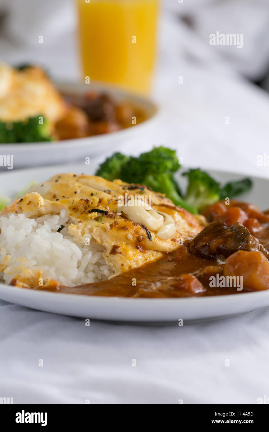 Japanese curry on rice with egg vegetable and orange juice at the back ...