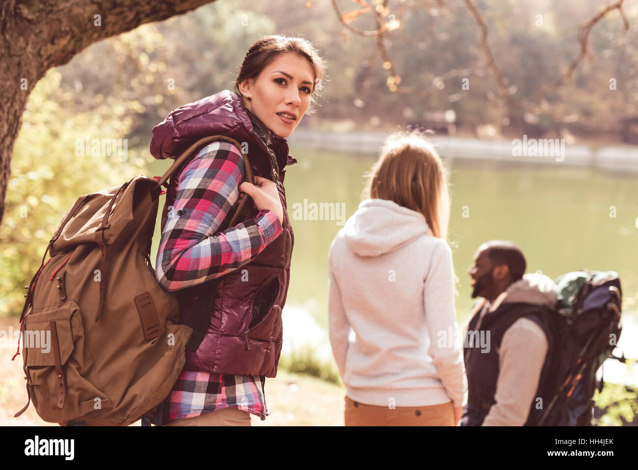 Group of young backpackers walking near river in autumn forest Stock ...