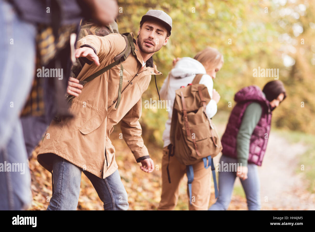 Four young friends backpackers walking in row in autumn forest Stock ...