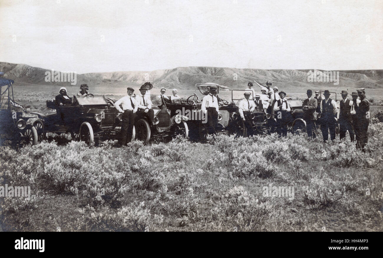 Line-up of Model T Ford motor cars with their drivers and passengers ...