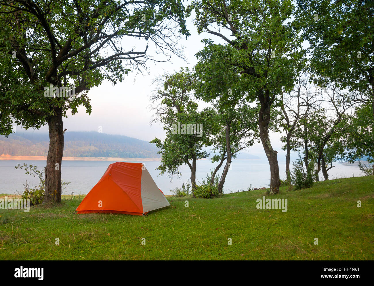 Orange camping tent on a river shore in a morning light Stock Photo - Alamy