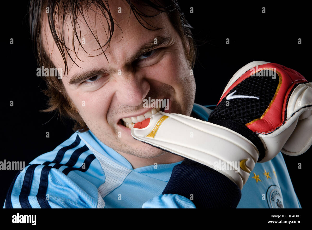 Portrait of a goalkeeper, fixing his glove with his teeth Stock Photo ...