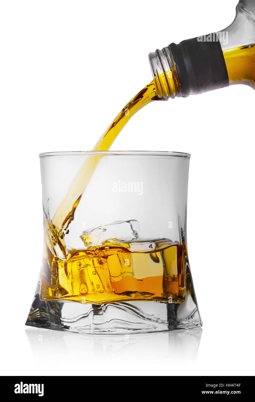 Whiskey pouring from a bottle into a glass with ice isolated on white ...