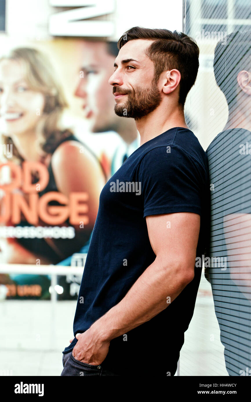 Handsome man in the city - in background a commercial poster with a ...