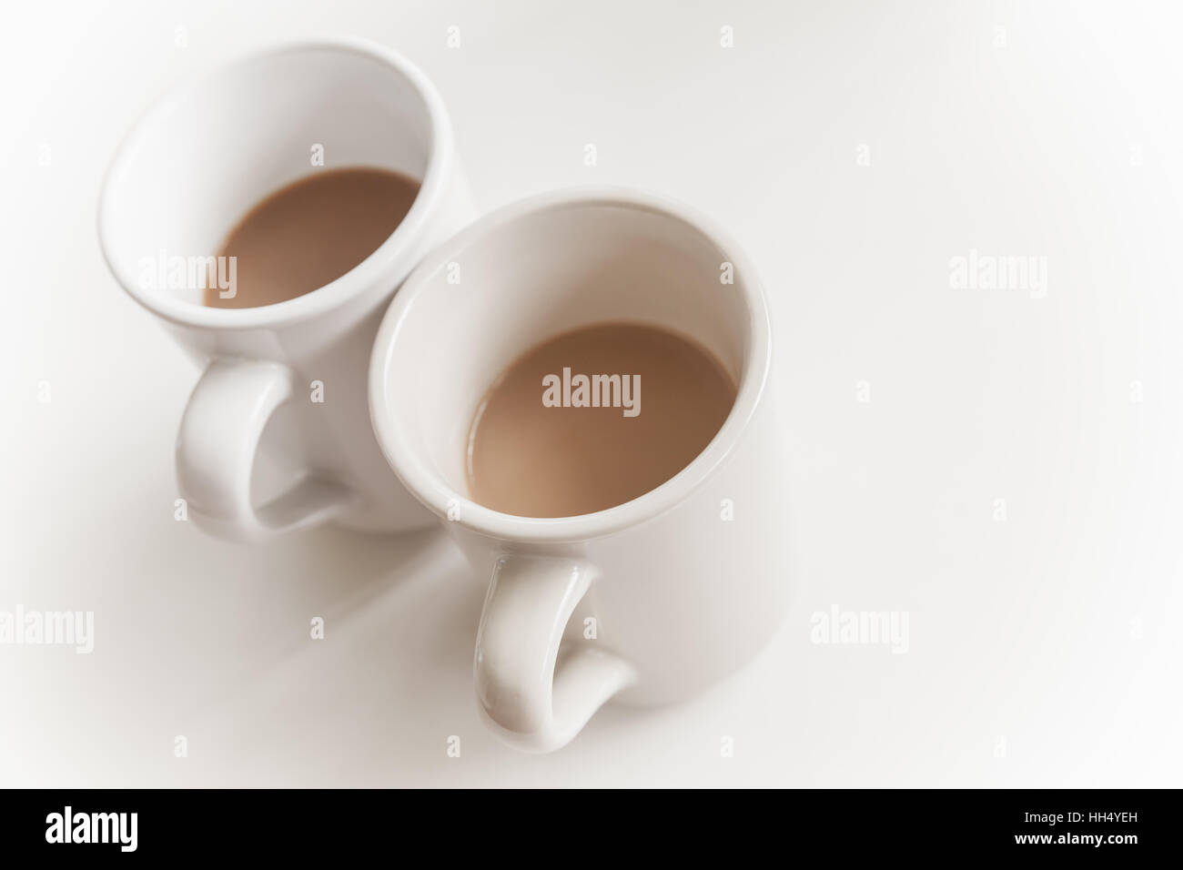 Two big cups full of coffee with milk stand on white table with soft ...