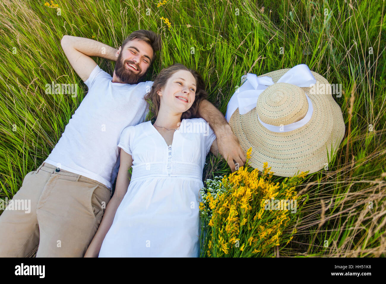 Happy young relaxed couple in love laying down on the grass overhead ...
