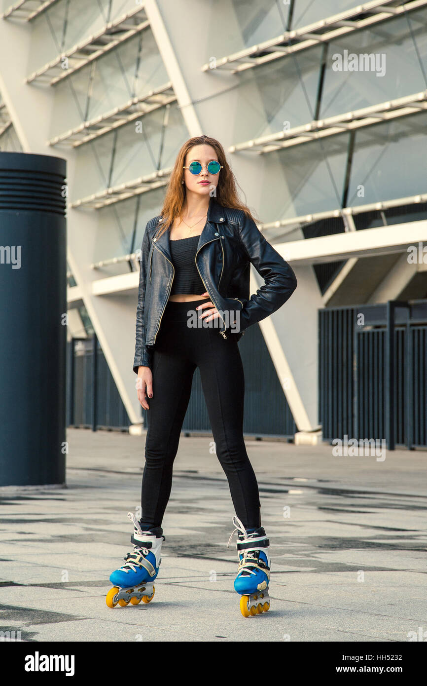 Girl on rollerblades standing in building background. Young fit women ...